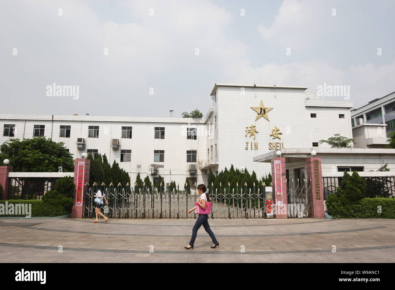 Chinese women walk past the factory of Dongguan Jian Plastic & Metal ...