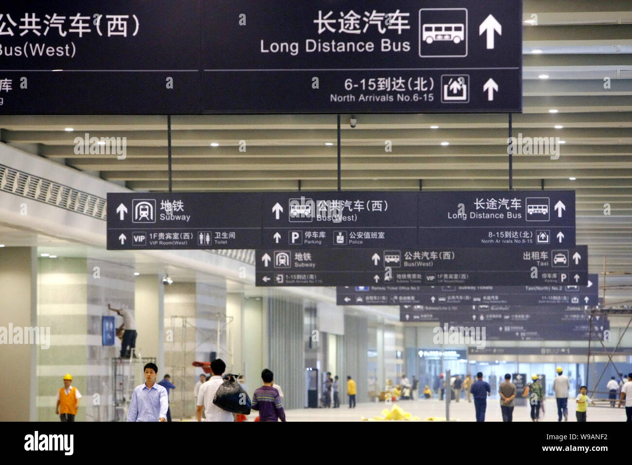 Chinese workers walk under direction signs in the Shanghai Hongqiao ...