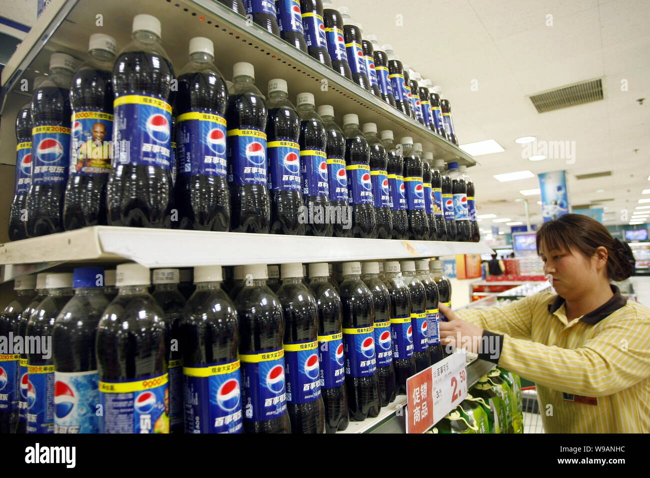 A Chinese employee puts bottles of Pepsi cola on the shelf at a ...
