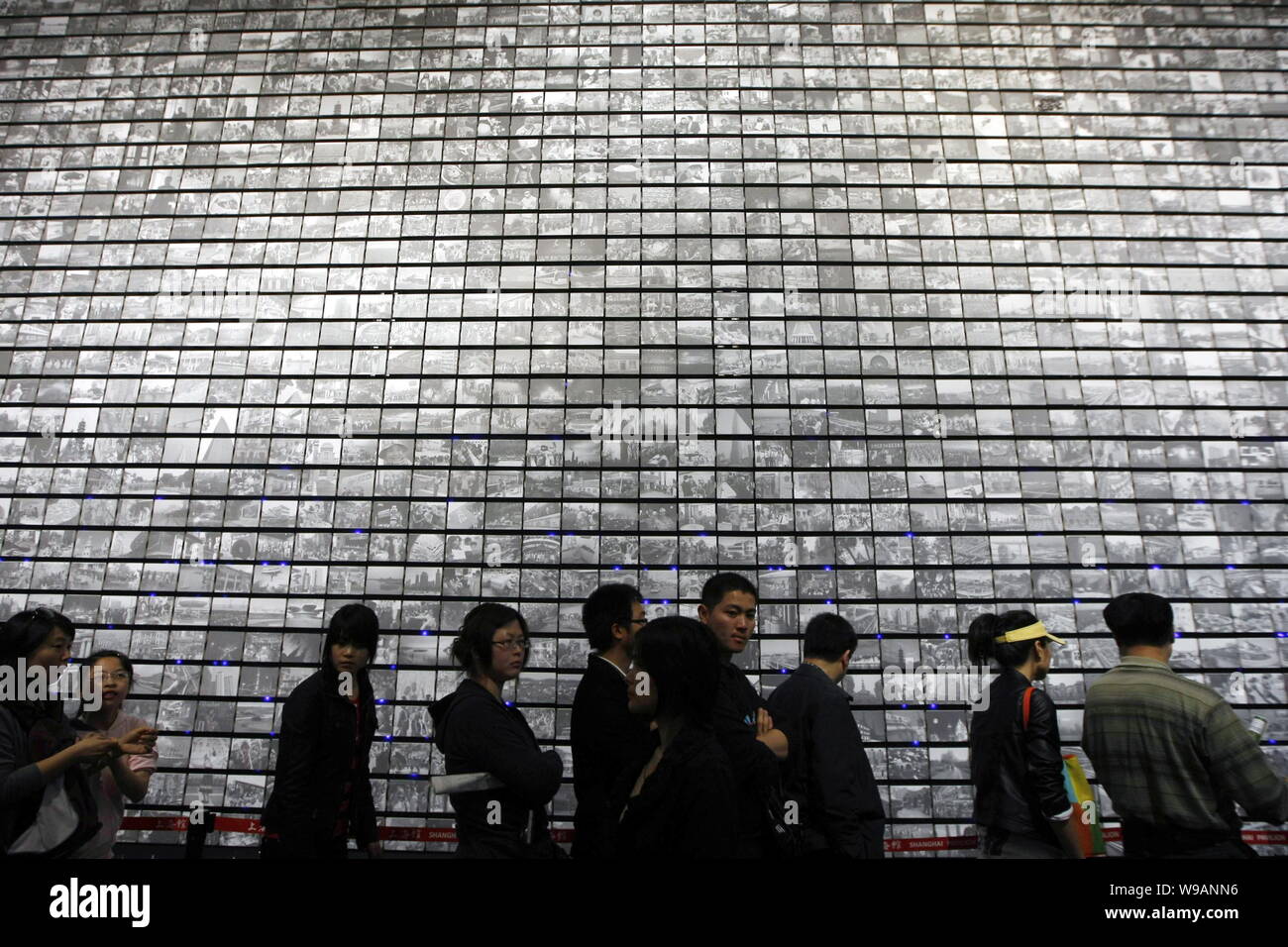 Visitors queue up in front of a wall of photos to enter the Shanghai ...
