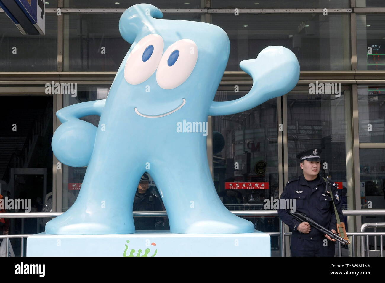 An armed Chinese policeman stands guard next to a sculpture of Haibao ...