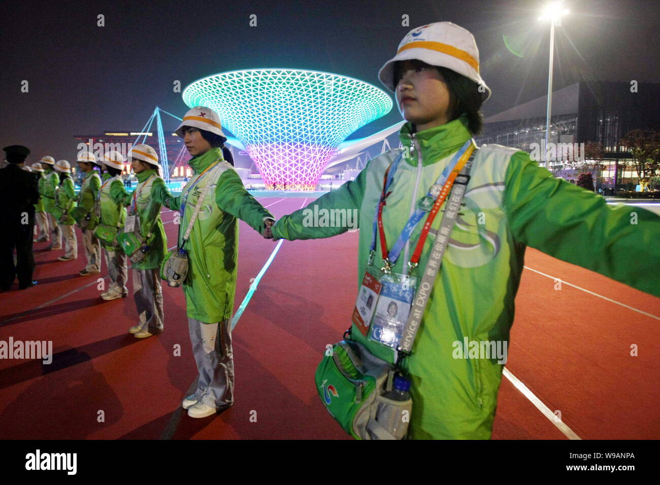 Chinese volunteers stand hand in hand in front of the Expo Axis in the ...