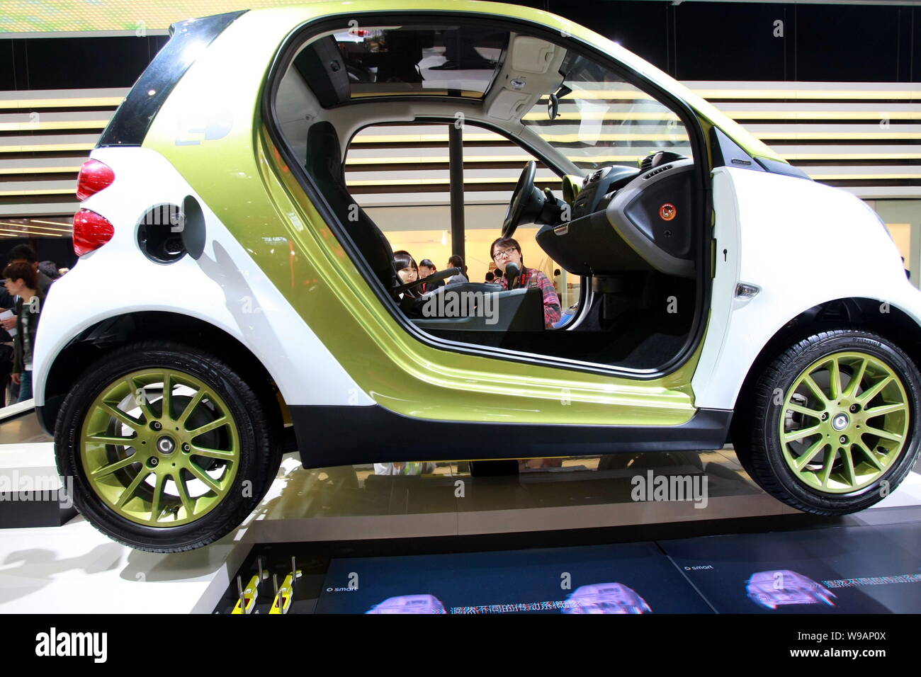 Visitors look at a SMART electric car of Mercedes-Benz at the 11th ...