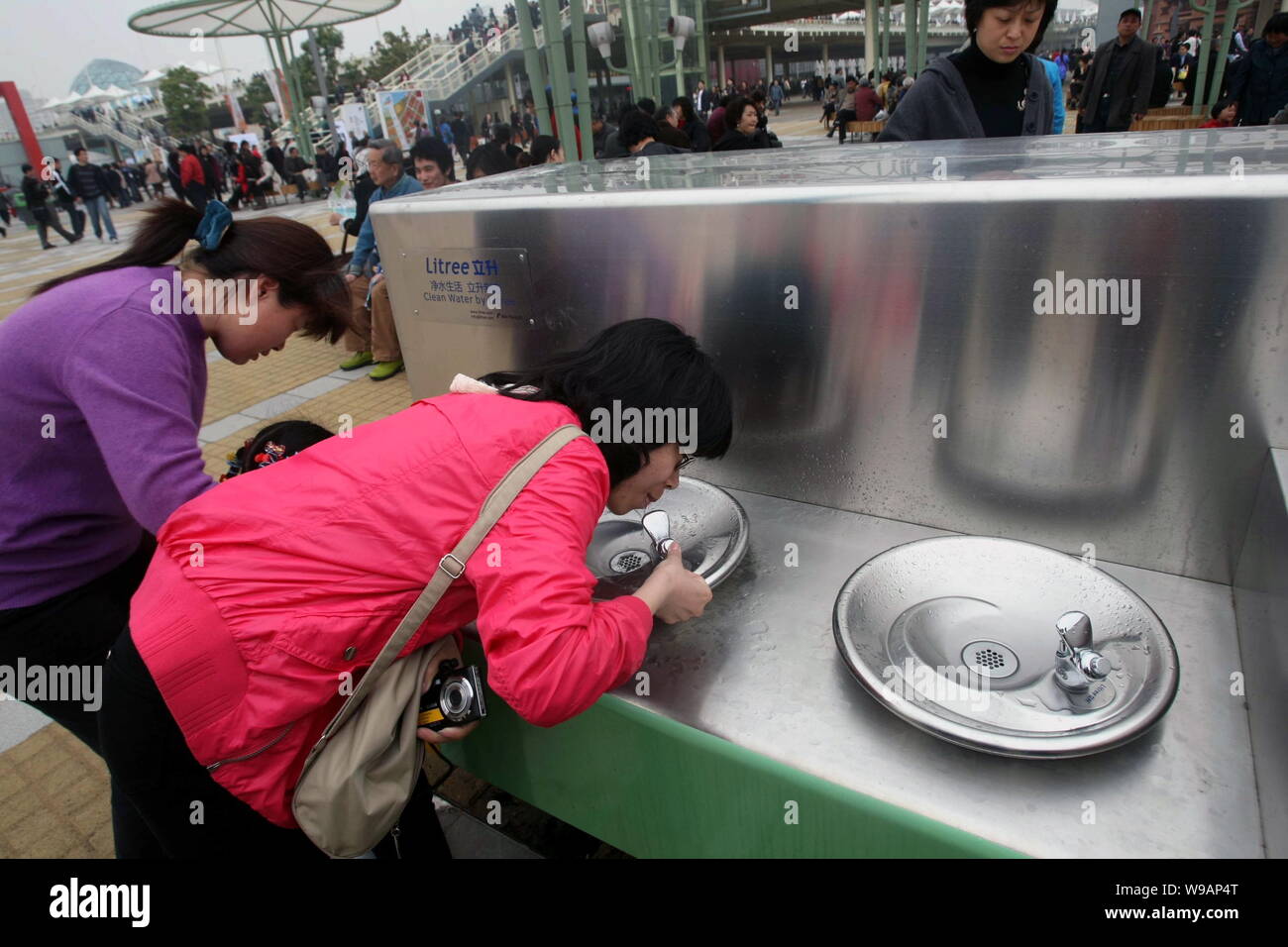Visitors drink water at a drinking water stand in the Expo site in ...