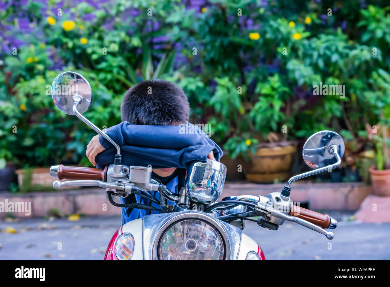 The boy sitting and sleeping on the motorcycle Stock Photo - Alamy