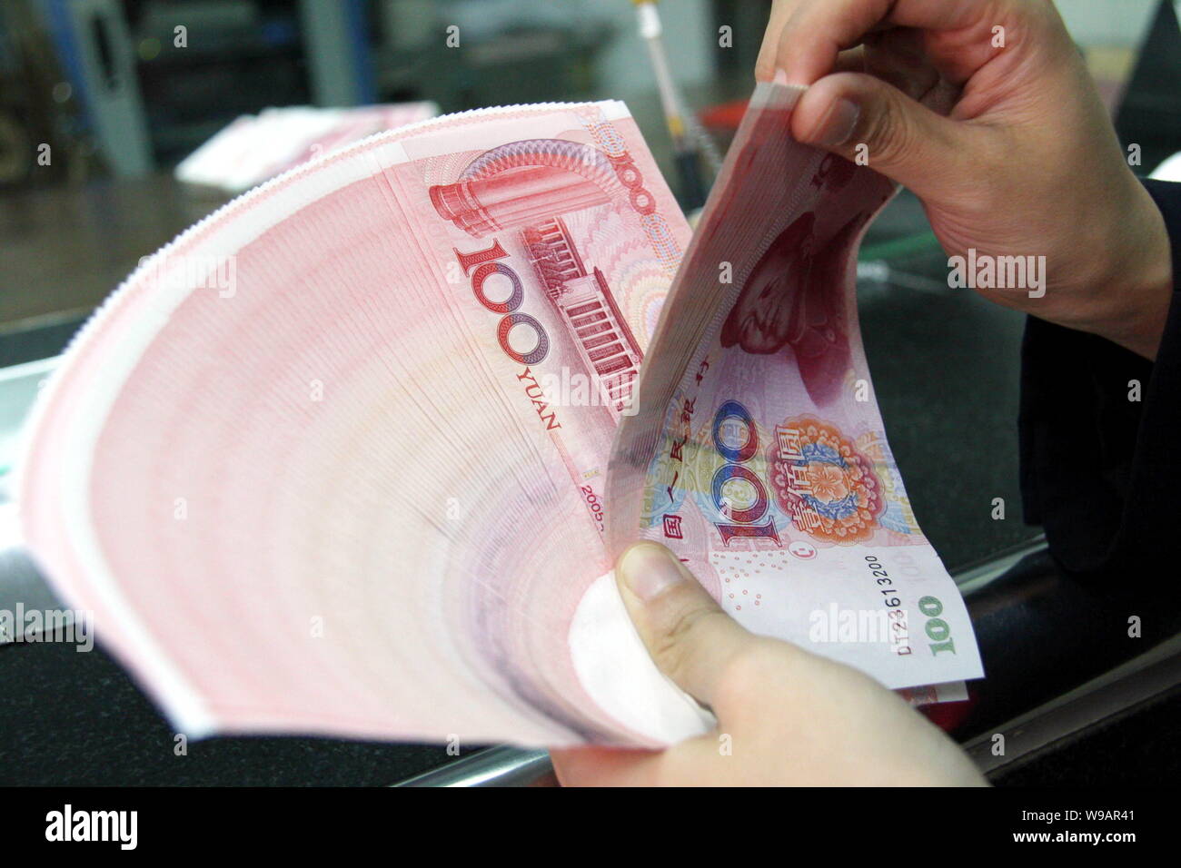 --FILE--A bank clerk counts RMB Yuan banknotes at a bank in Nantong ...