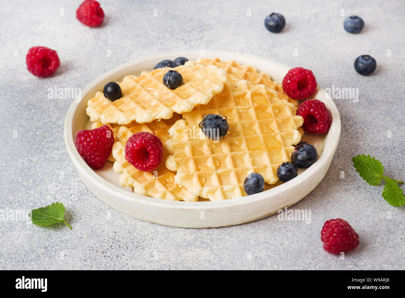 Corrugated waffle cookies with fresh raspberries and blueberries on a ...