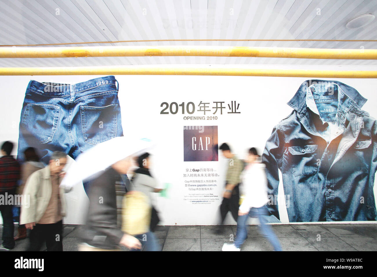 Local residents walk past an advertisement of Gap in Shanghai, China ...