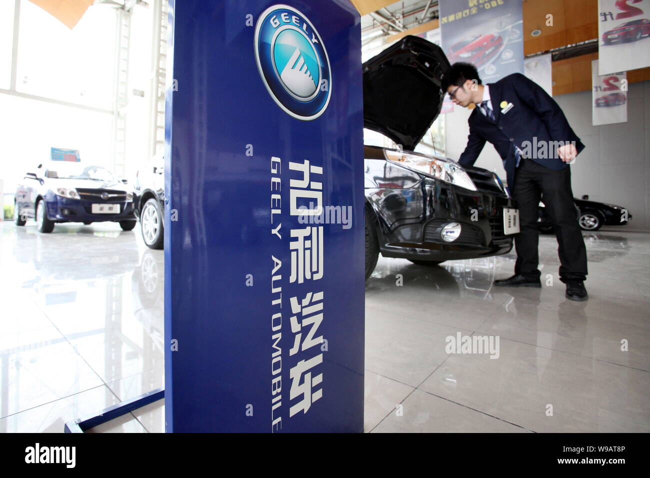 A Chinese employee checks a Geely car at a Geely dealership in Shanghai ...