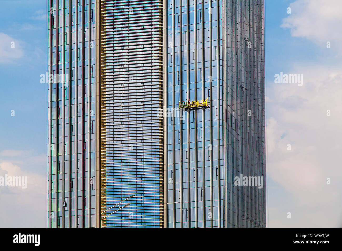 Workers in a hanging cradle wash windows in a modern office building ...