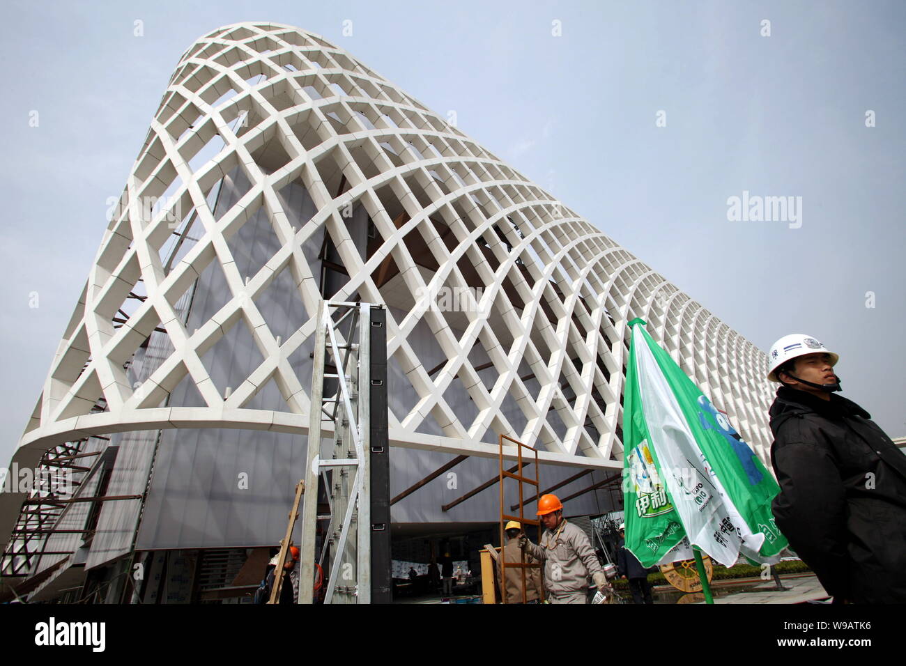 A Chinese security stands guard next to workers laboring at the ...