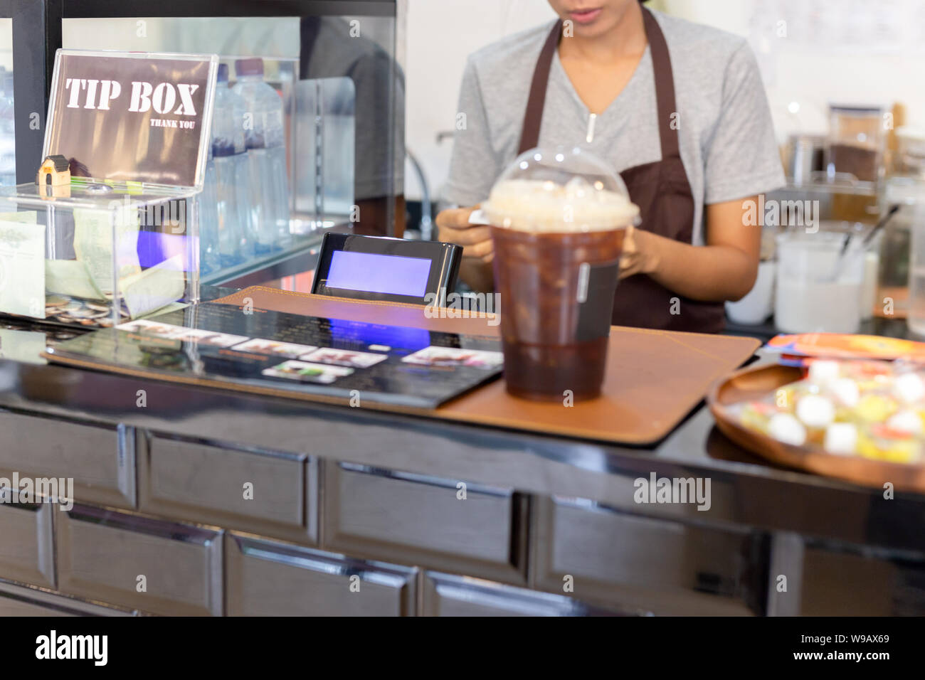Selected focus cash register with woman barista working behind the ...