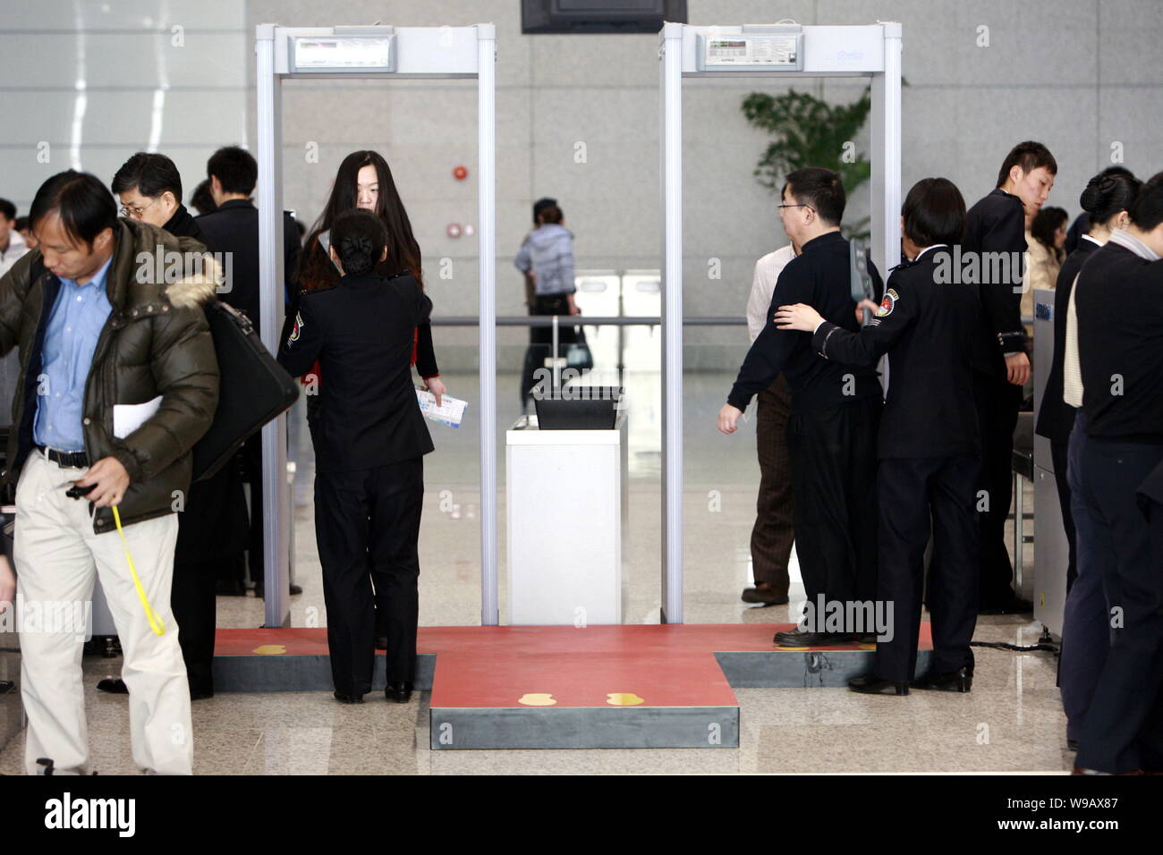 Chinese airport workers scan passengers for security check in the ...