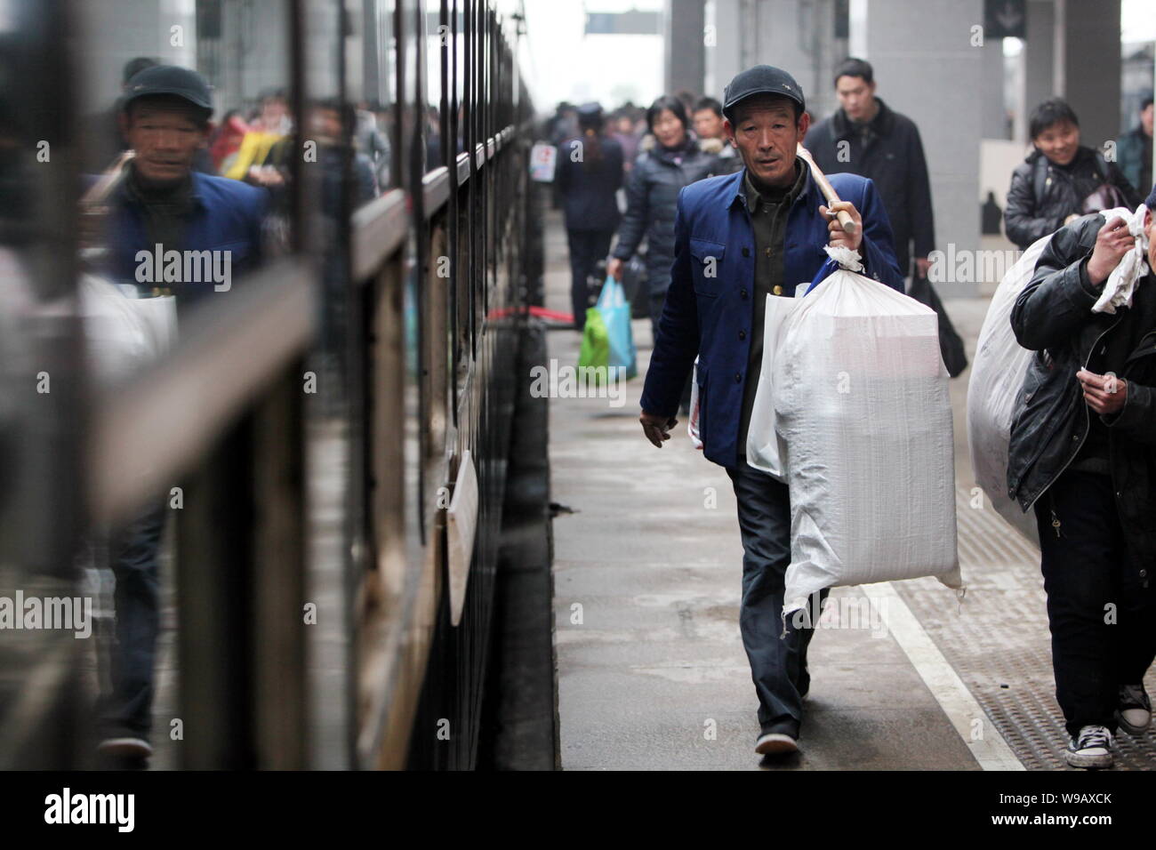 Chinese migrant workers and other passengers walk towards their trains ...