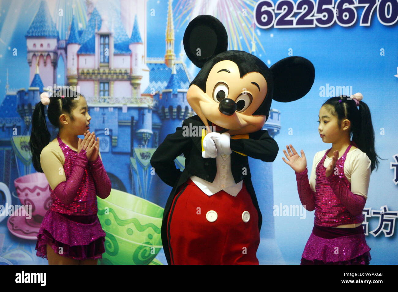 Mickey Mouse poses between two young girls at a press conference for ...