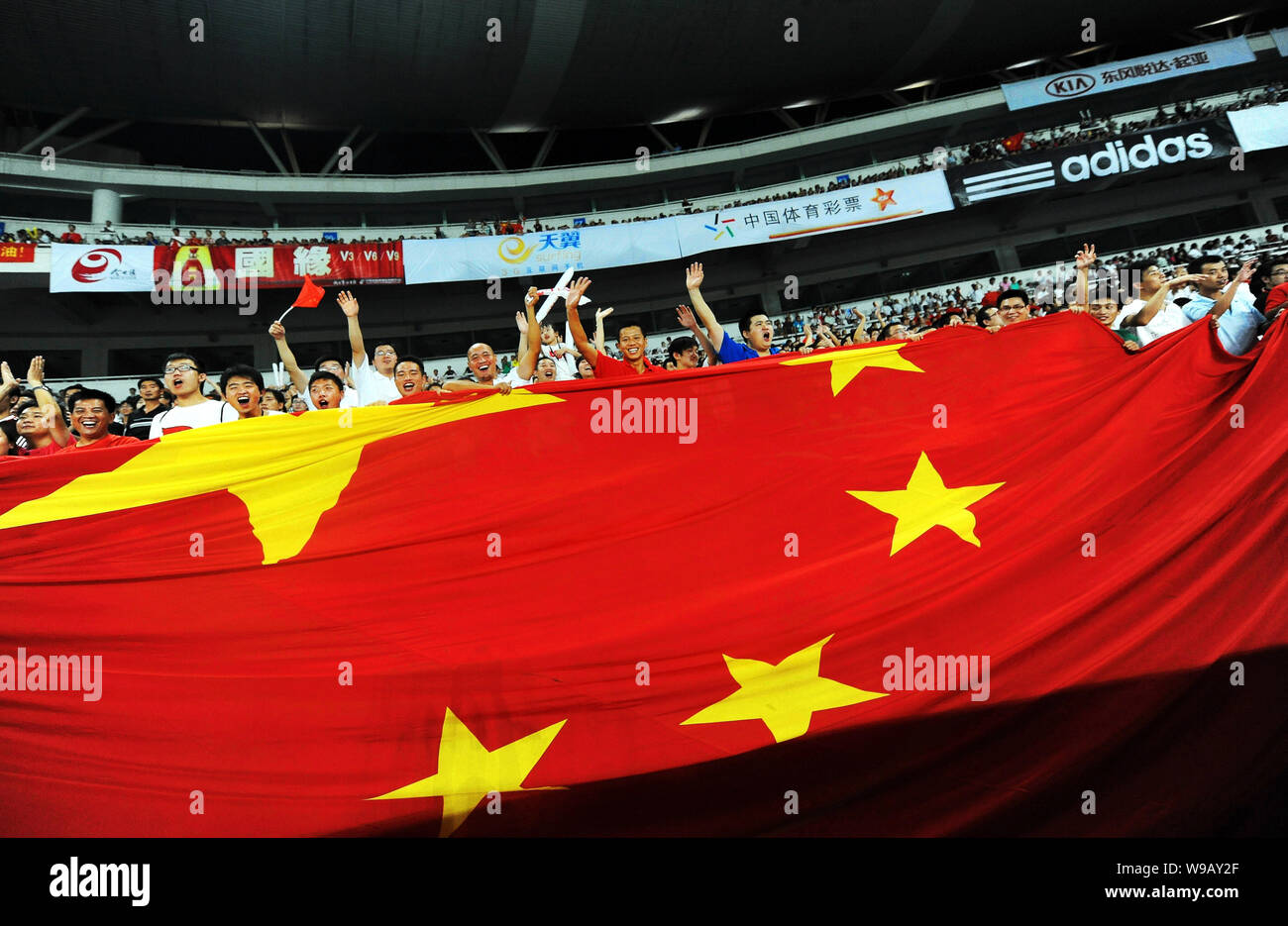 Chinese football fans cheer behind a Chinese national flag in a ...