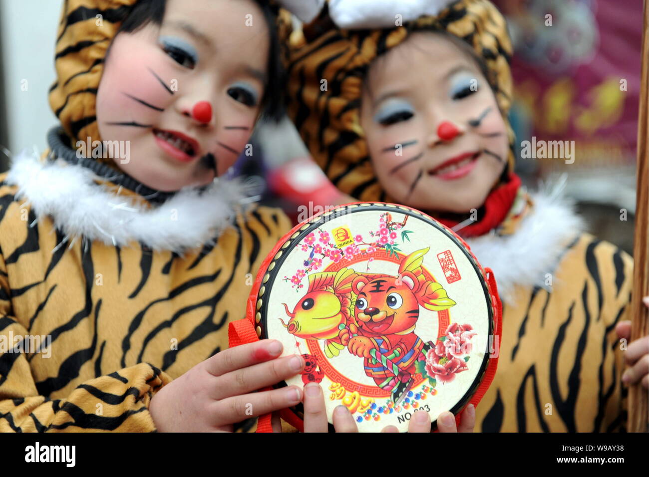 Chinese girls dressed like the tiger show a hand drum printed with a ...
