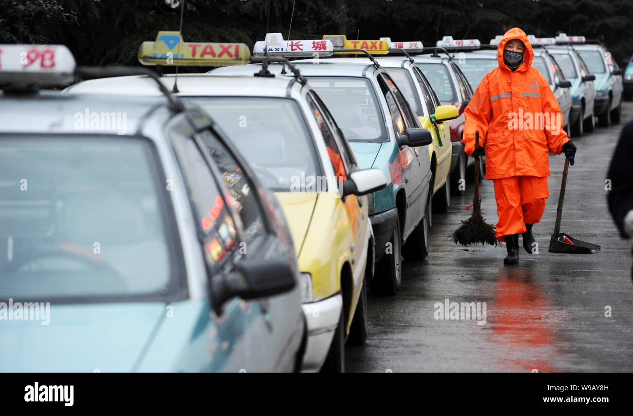 A cleaner walks past a long queue of taxis to be refueled with ...