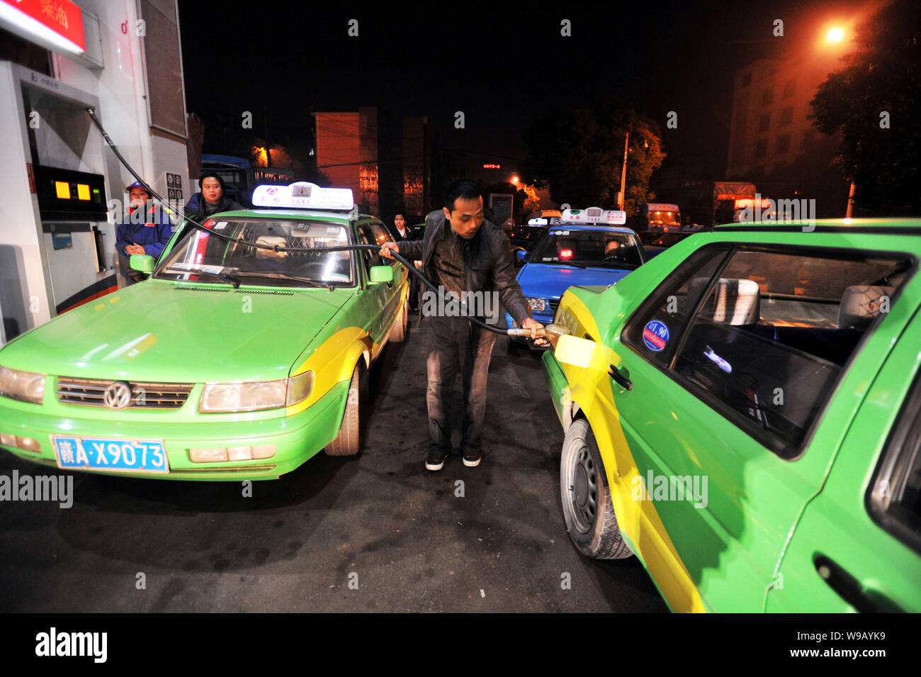 A Chinese taxi driver refuels his car at a gas station before the fuel ...