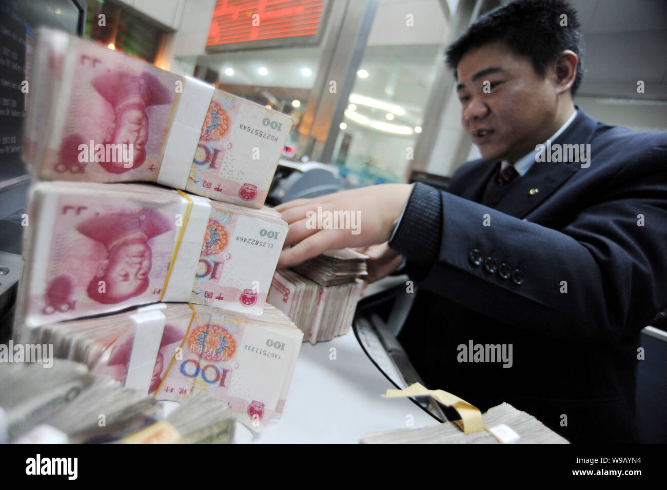 A Chinese clerk counts RMB (renminbi) yuan banknotes at a bank in Haian ...