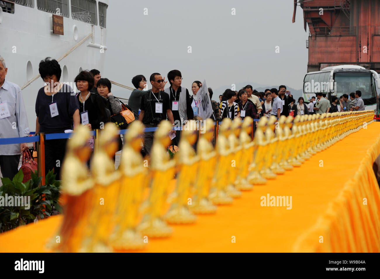 Chinese tourists walk past a row of golden statues of Buddhist goddess ...