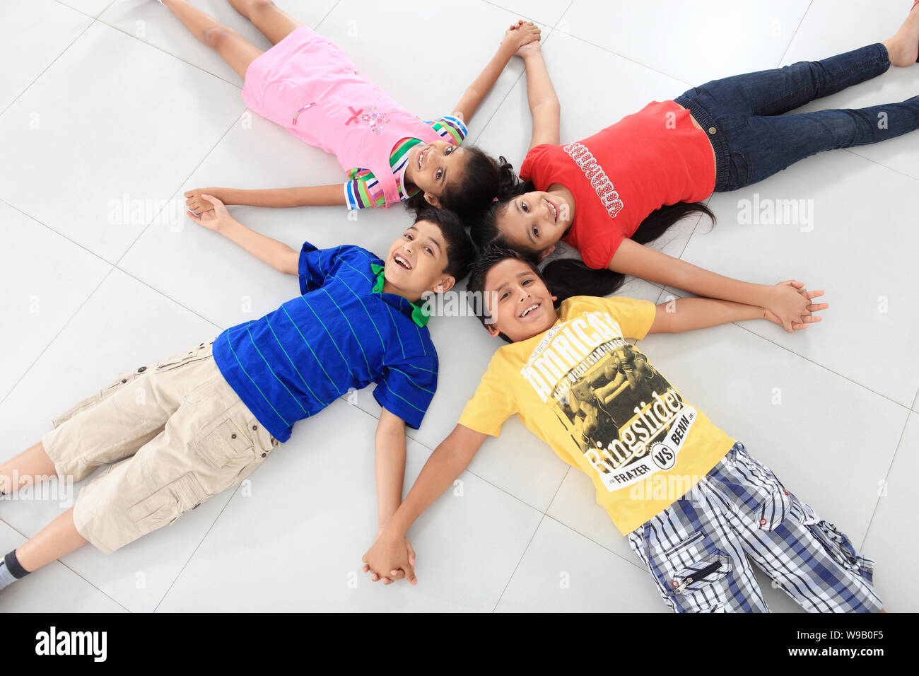 Group of children lying on floor and smiling Stock Photo - Alamy