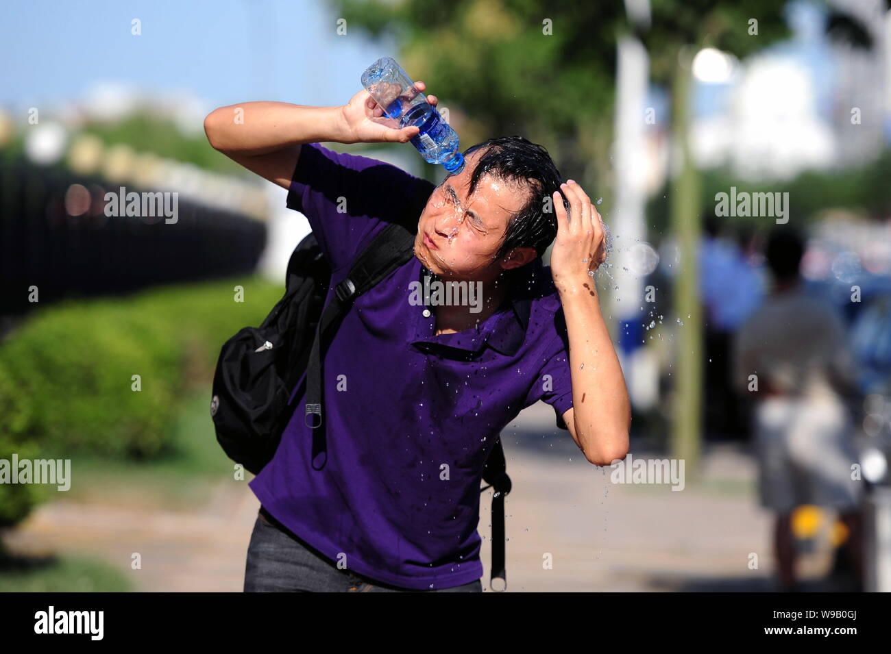 A Chinese man pouring water on his head to cool himself off in ...