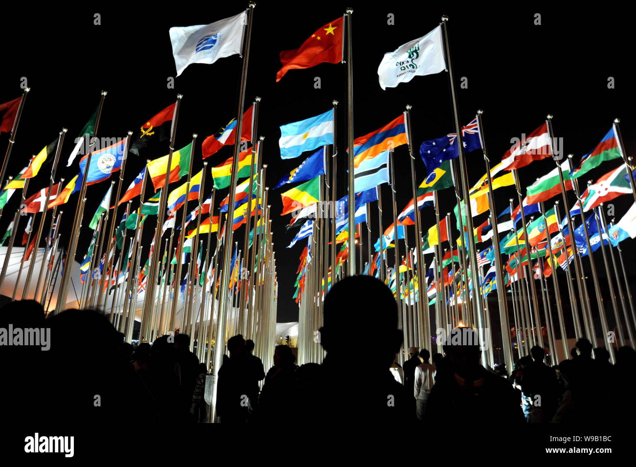 Visitors gather under national flags of the countries participating in ...