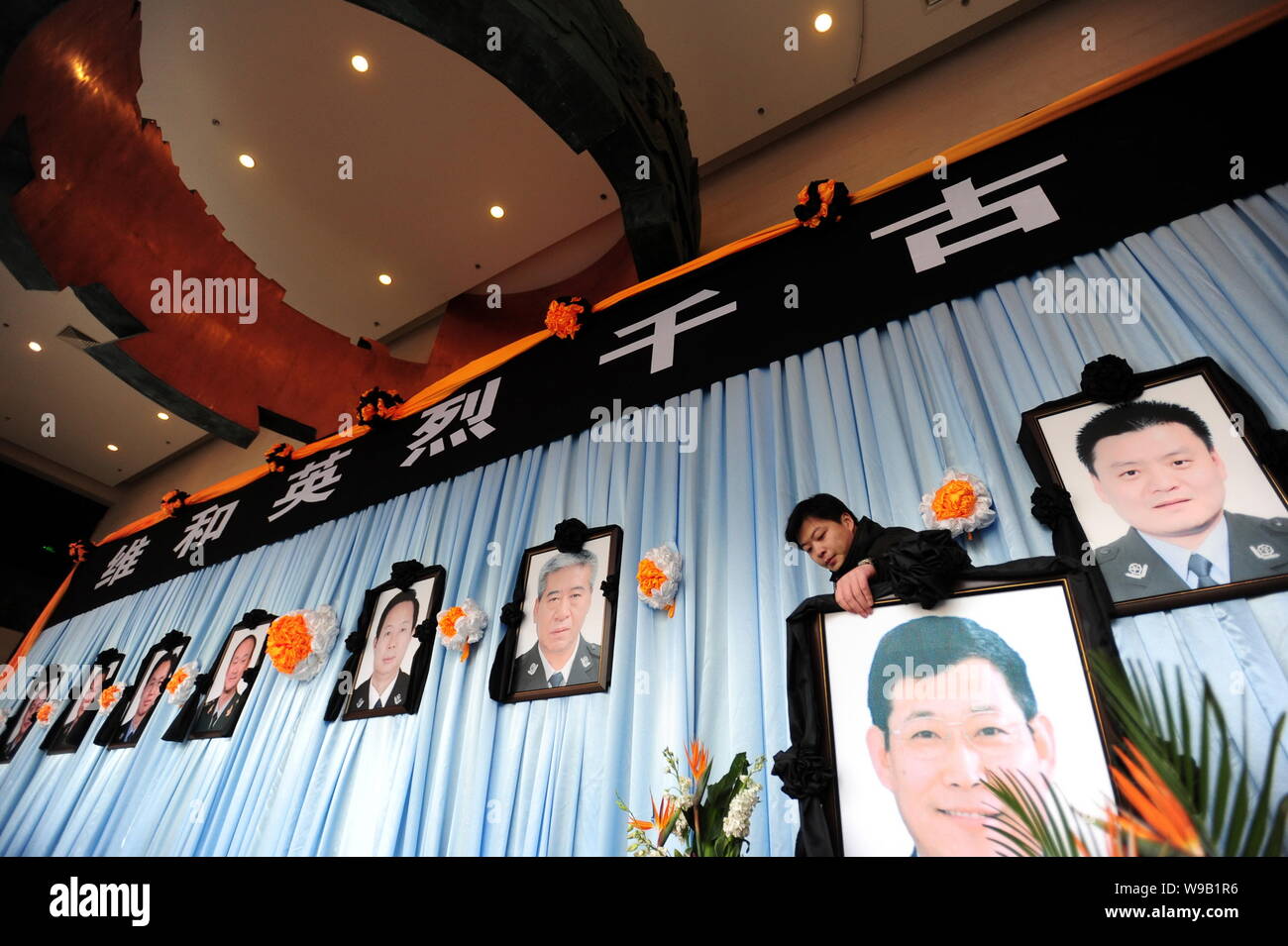 A Chinese worker hangs portraits of the eight police officers who died ...