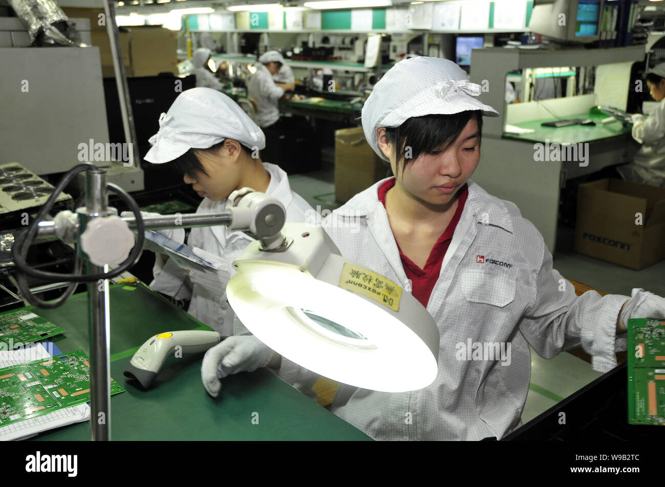 Chinese Foxconn workers check integrated circuit boards in a workshop ...