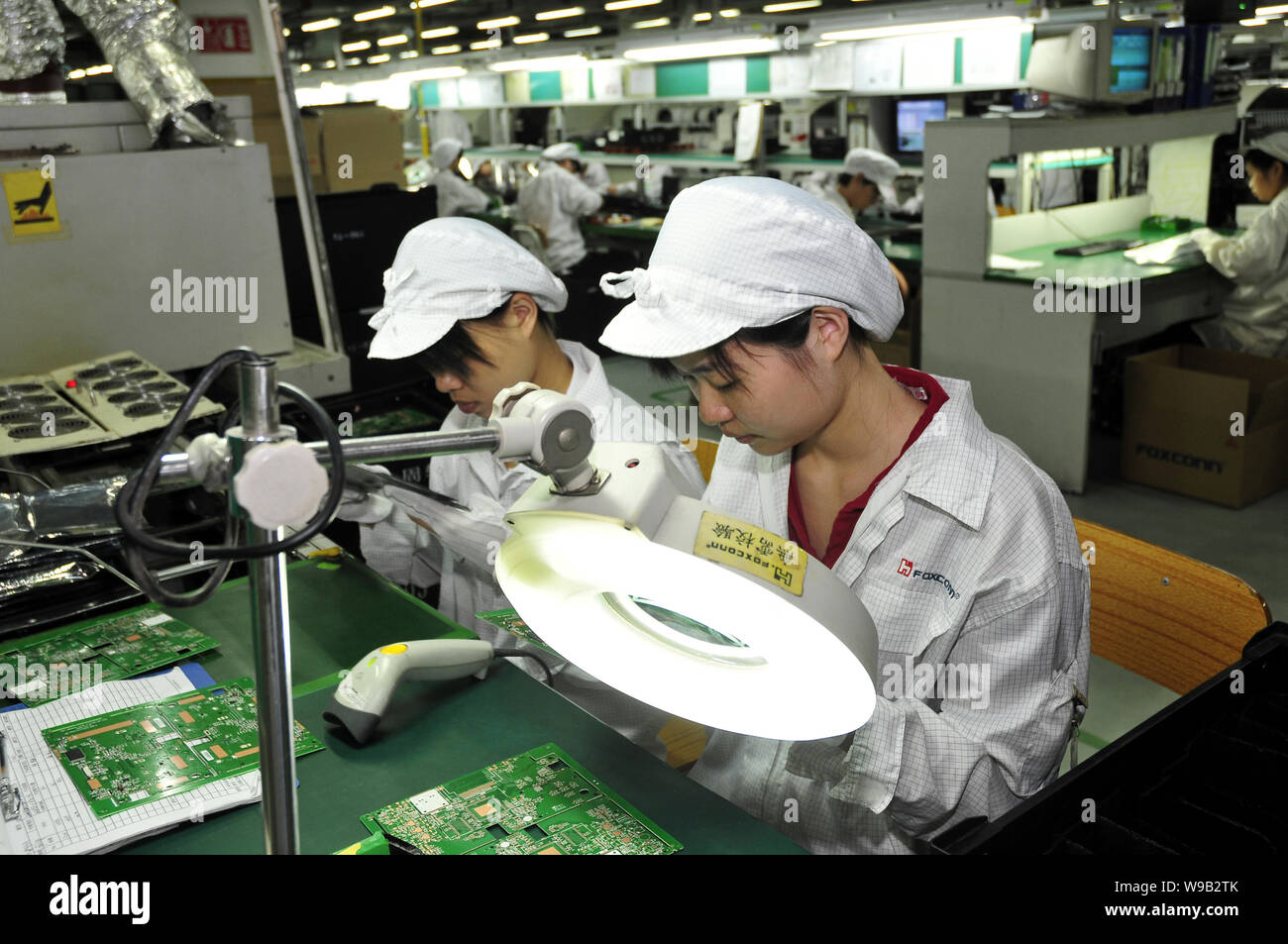Chinese Foxconn workers check integrated circuit boards in a workshop ...