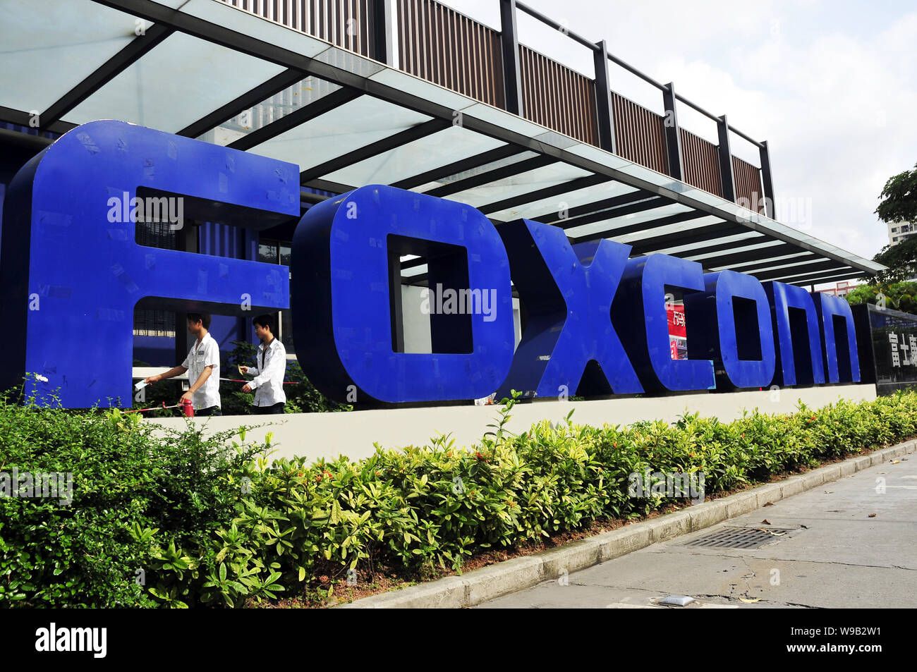 Chinese Foxconn employees walk past the logo of Foxconn at the south ...