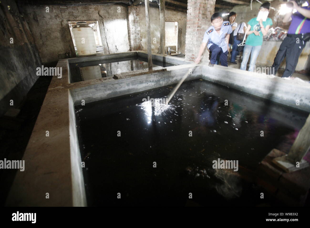 A Chinese law enforcement officer checks waste water at a gutter oil ...