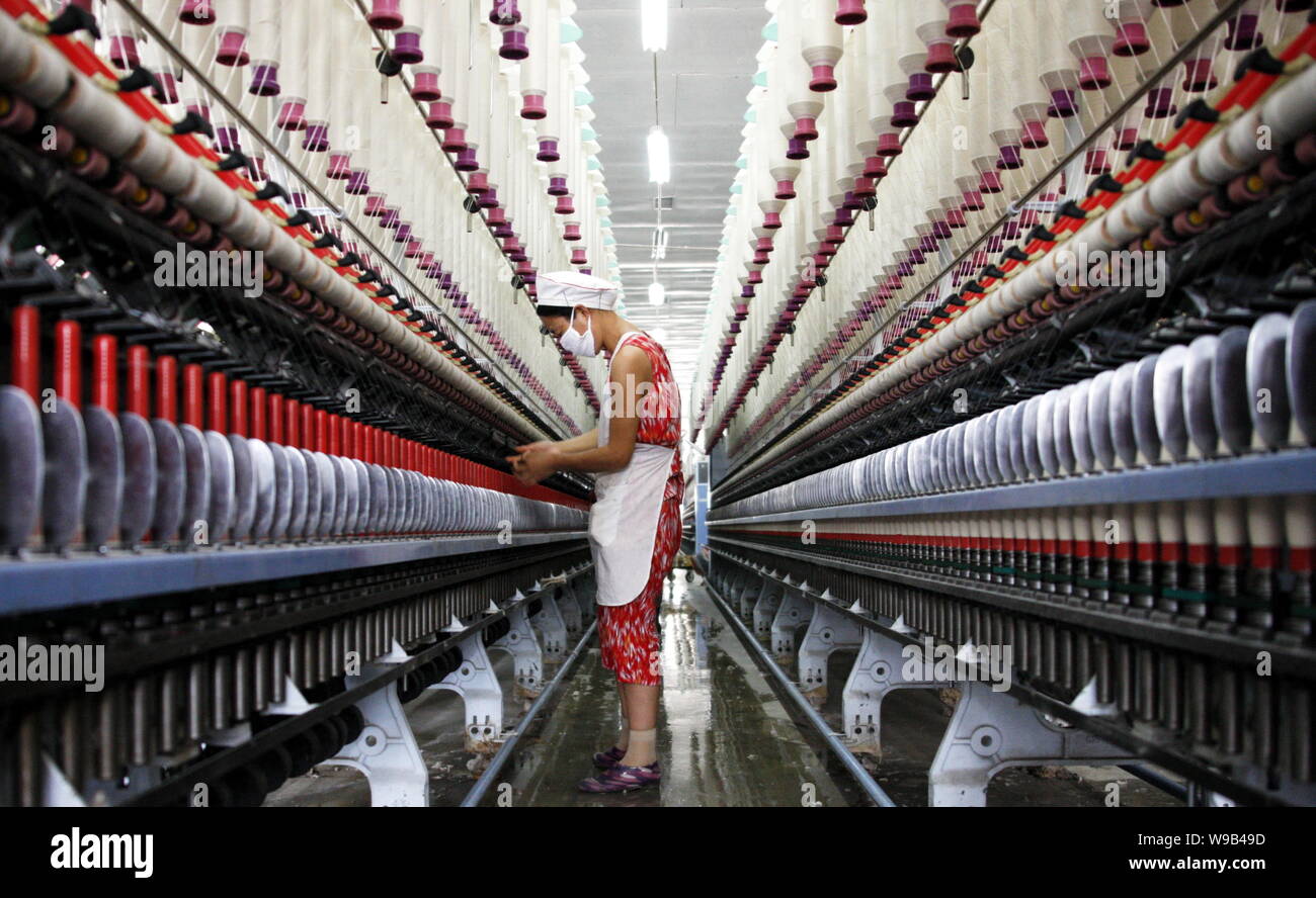A female Chinese factory worker checks yarn on the spinning machine at ...