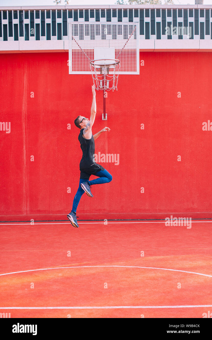 A basketball player at an outdoor stadium trains, lifting his hands up ...