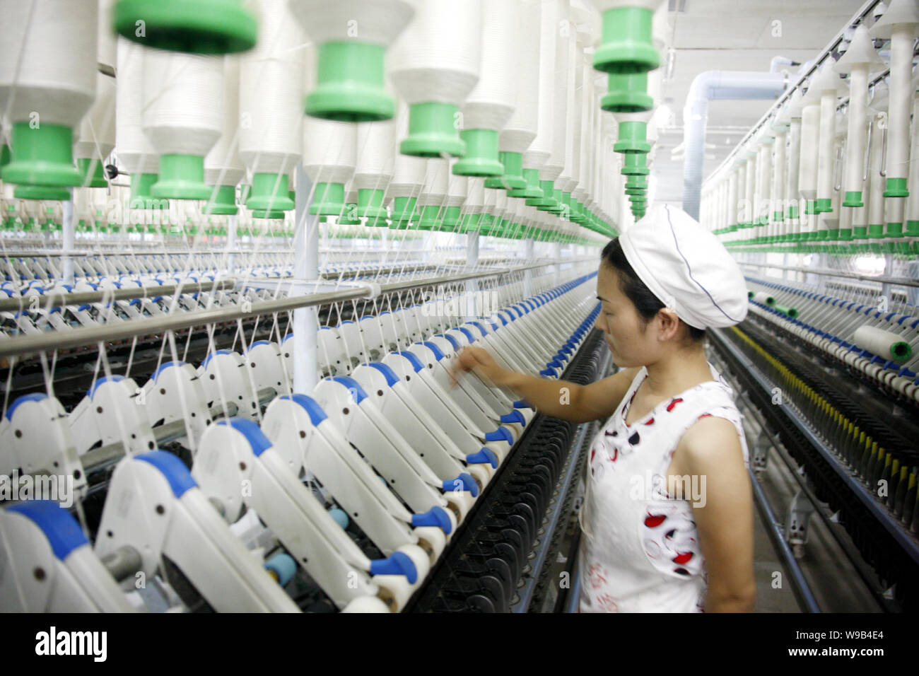 --FILE--A female Chinese factory worker checks yarn on a spinning ...