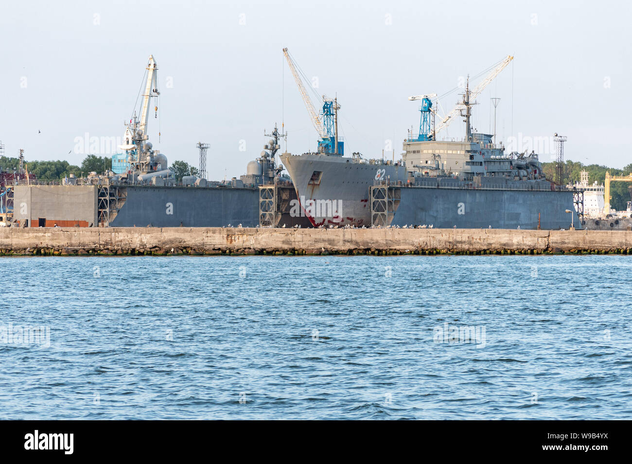 Large iron navy ships in shipyard for repair. Big crane in dockyard ...