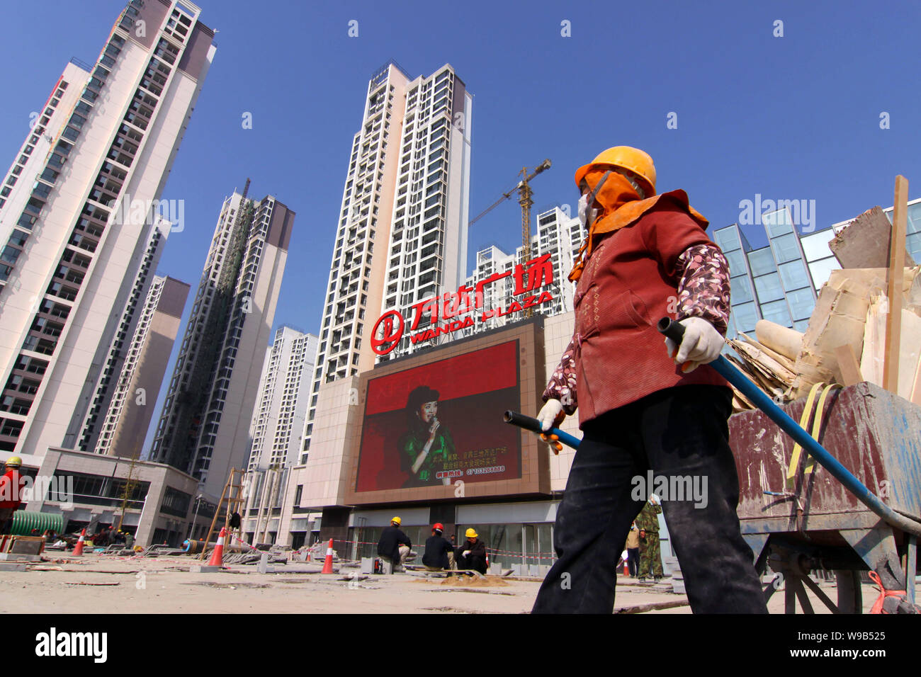Chinese migrant workers labor on a jobsite next to a residential ...