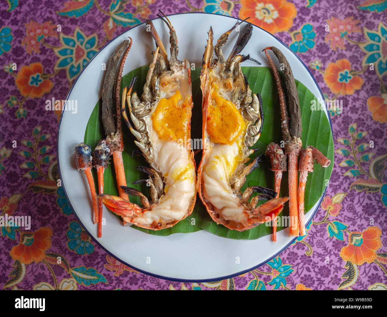 Flat lay of roasted grilled giant river shrimp or prawn on green banana ...