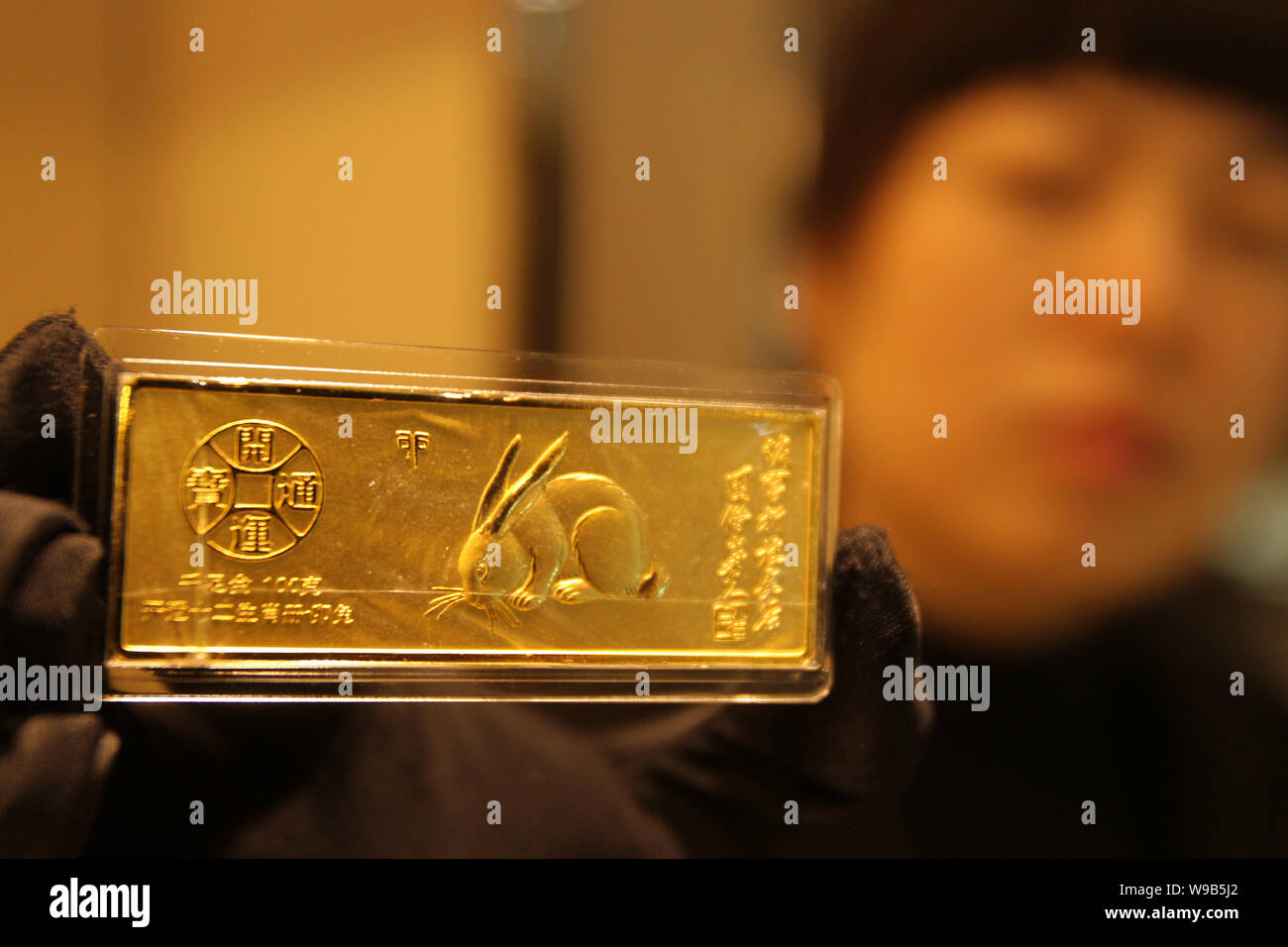 --FILE--A Chinese staff shows a gold bar marking the Year of the Rabbit ...