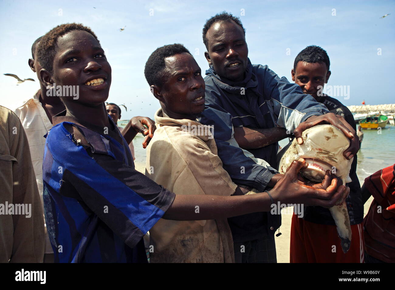Somali fishermen show a fish they hunted at the harbor in Bosaso ...