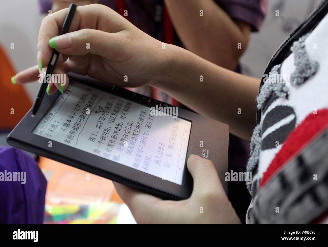 A Chinese visitor tries a Hanvon e-book reader, manufactured by Hanwang Technology Co., Ltd ...