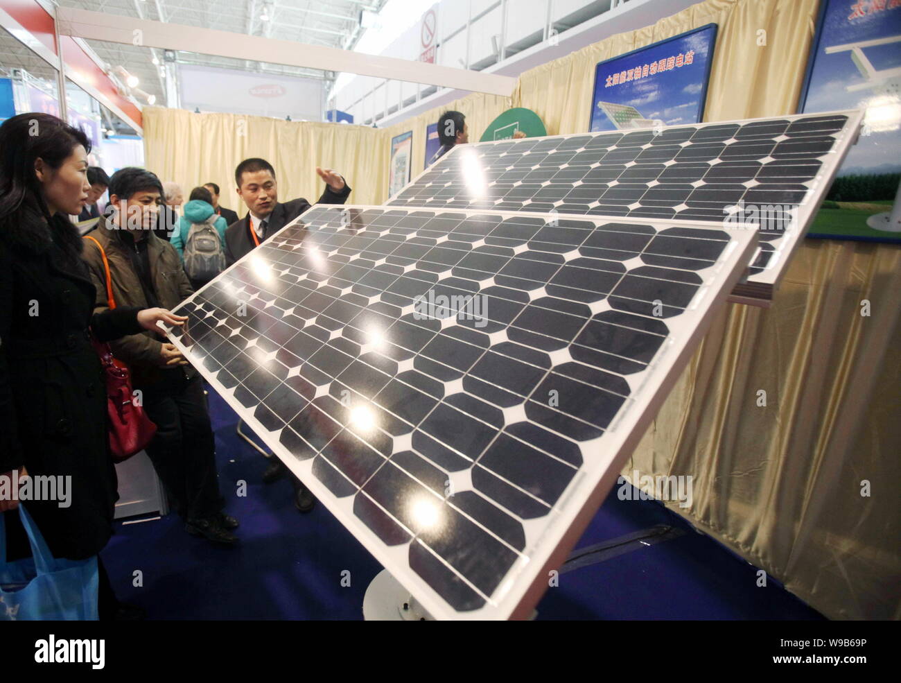 Visitors look at solar panels during an exhibition in Beijing, China ...