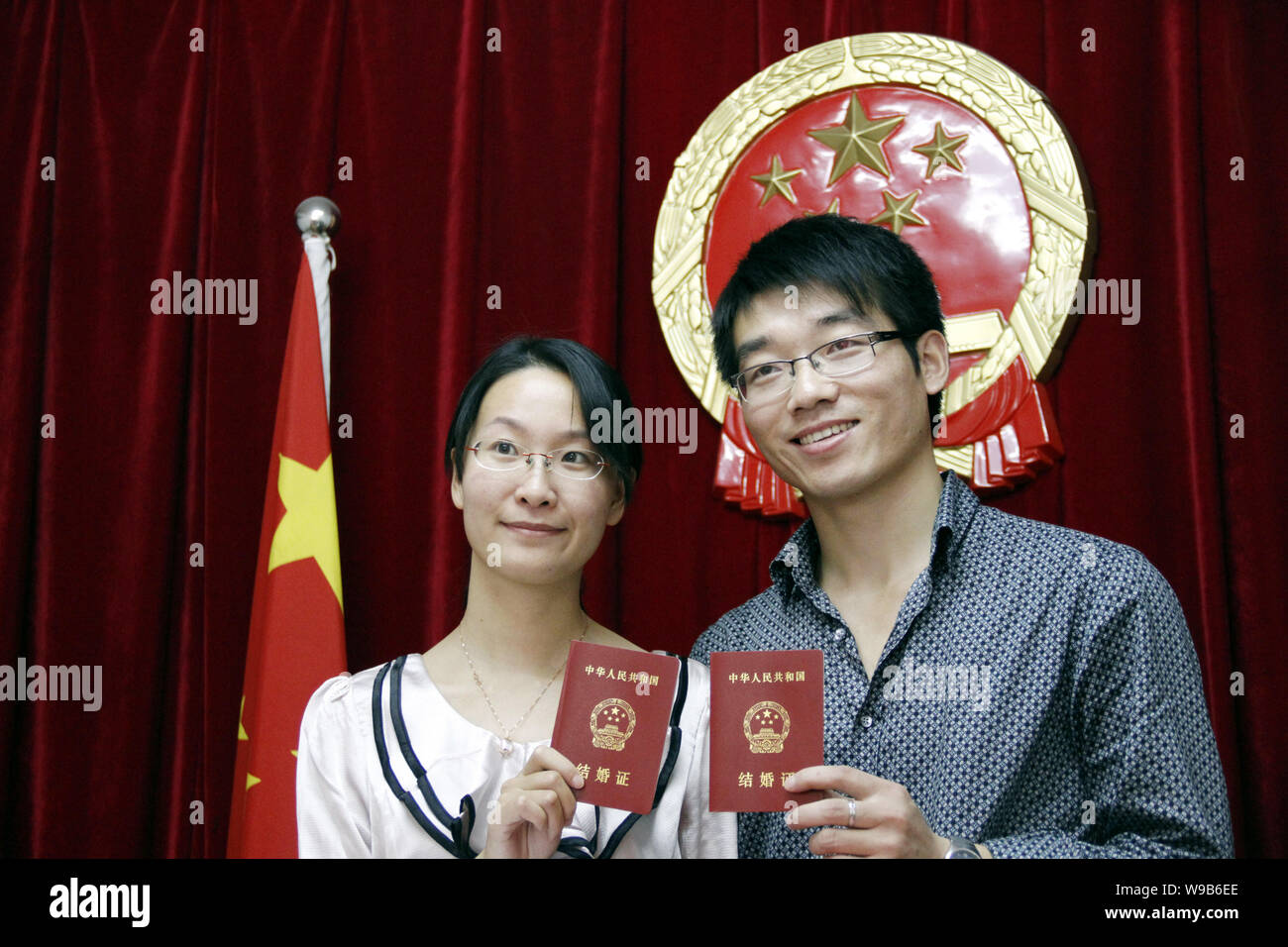 A Chinese young couple holding their marriage certificates pose for ...