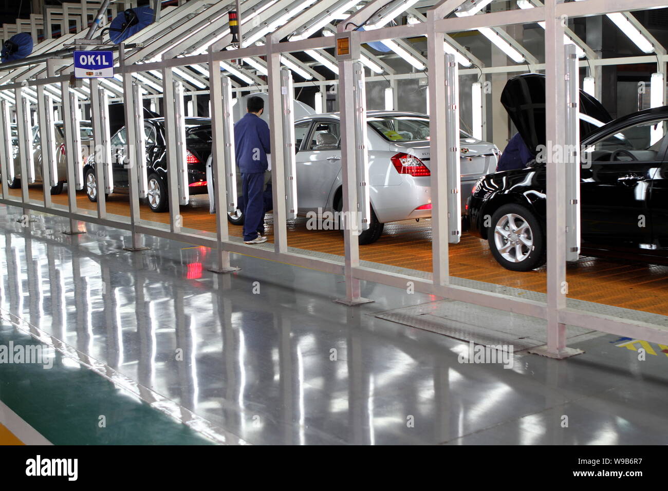 Chinese factory workers check Geely Emgrand cars on the assembly line ...