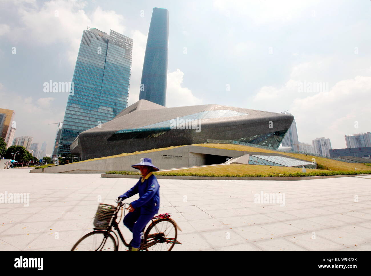 A Chinese cyclist rides a bicycle past the Guangzhou Opera House in ...