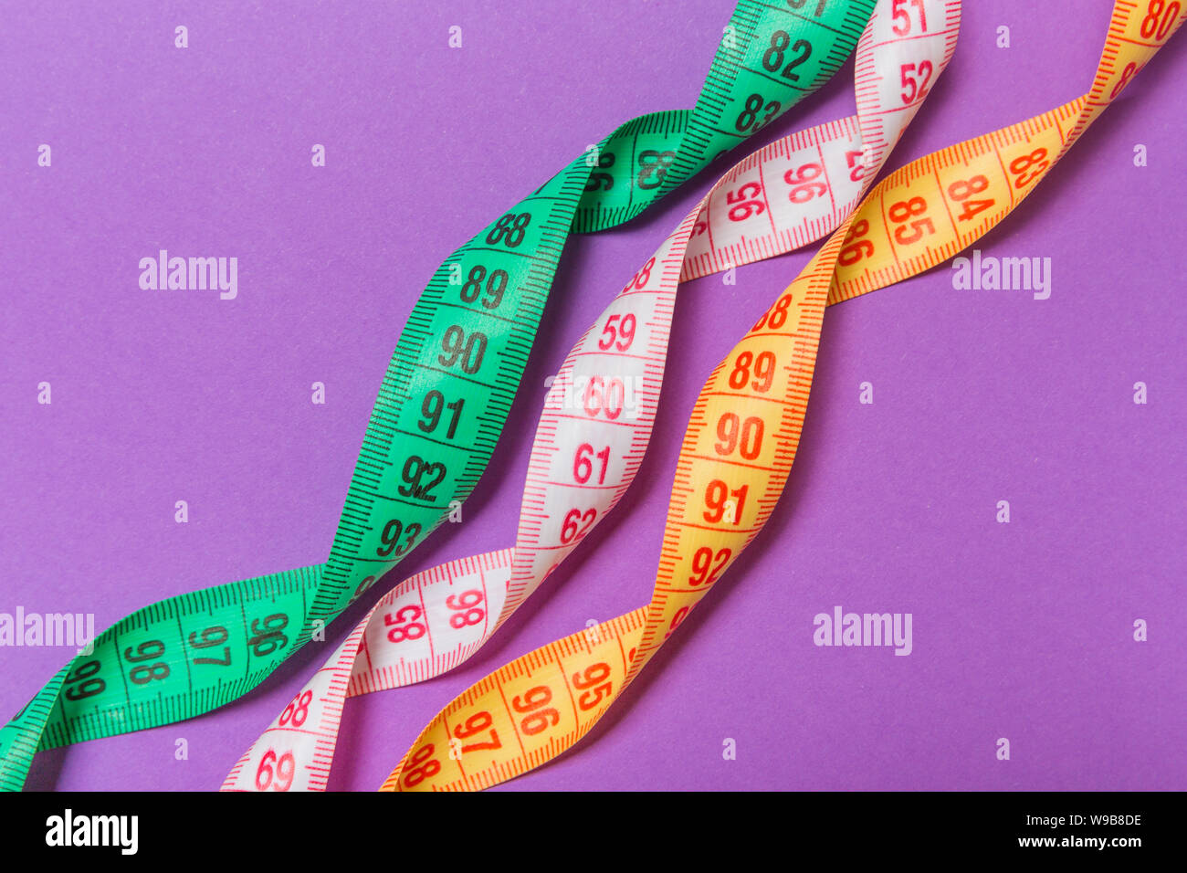 Perspective view of spiral colorful measure tapes on purple background ...