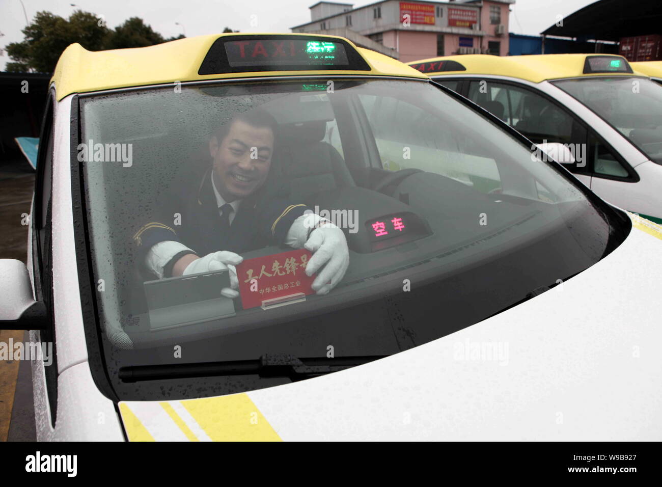 A Chinese taxi driver sets up a signboard in his Volkswagen Touran taxi ...