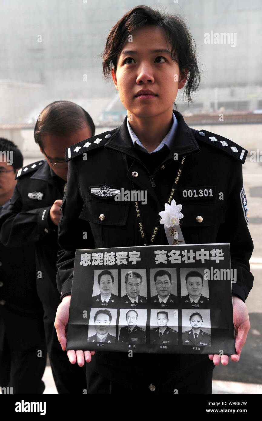 A Chinese police officer holds a newspaper showing portraits of the ...