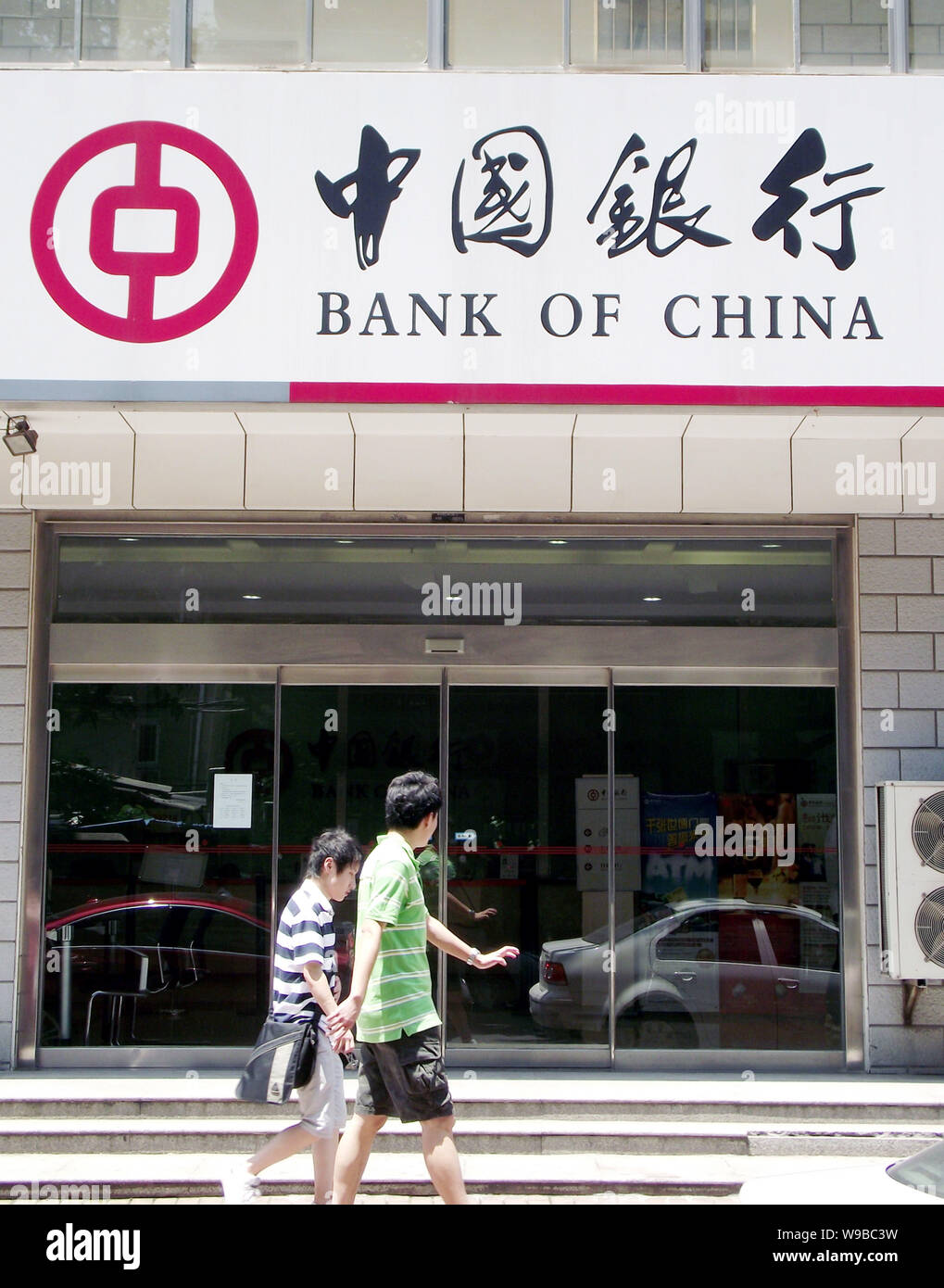 --FILE--Local Chinese residents walk past a branch of Bank of China ...